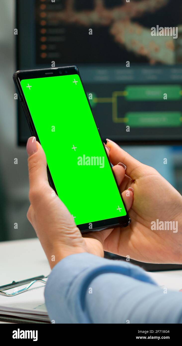 Medic in scientific laboratory holding phone with greenscreen wearing ...