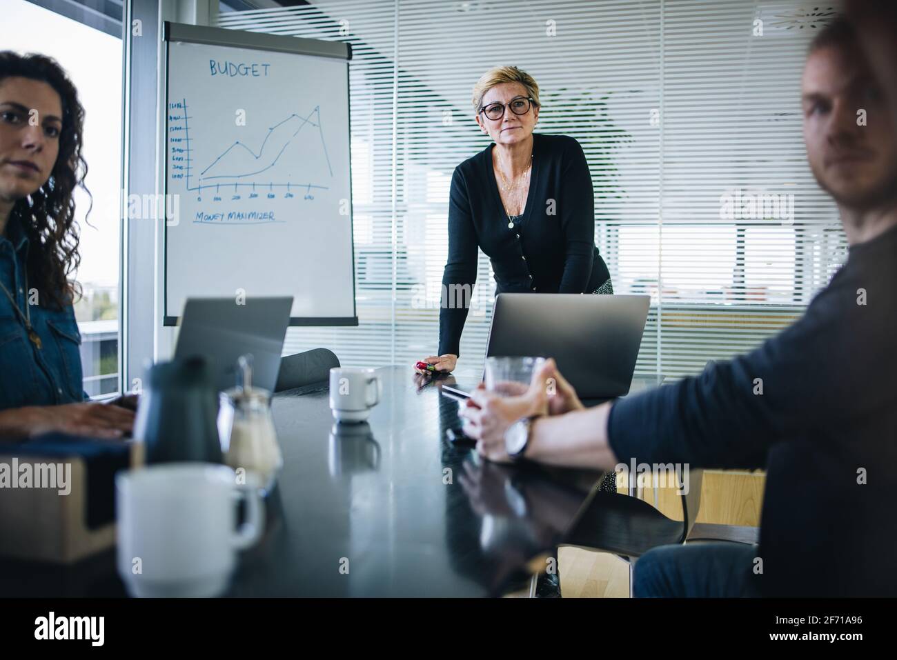 Senior businesswoman standing at conference table and listening to a ...