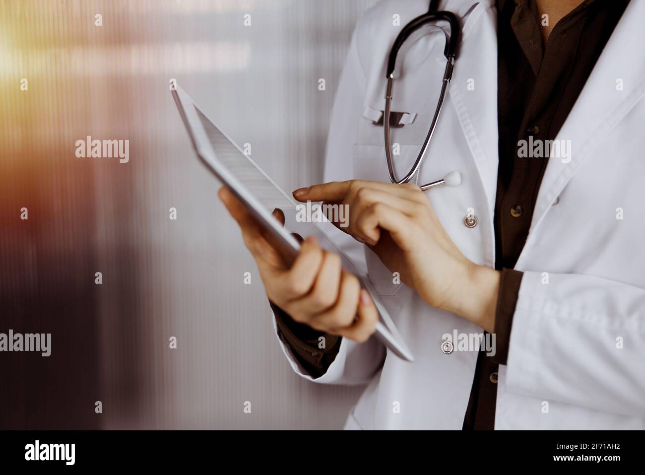 Unknown female doctor using tablet computer in sunny clinic. Perfect ...
