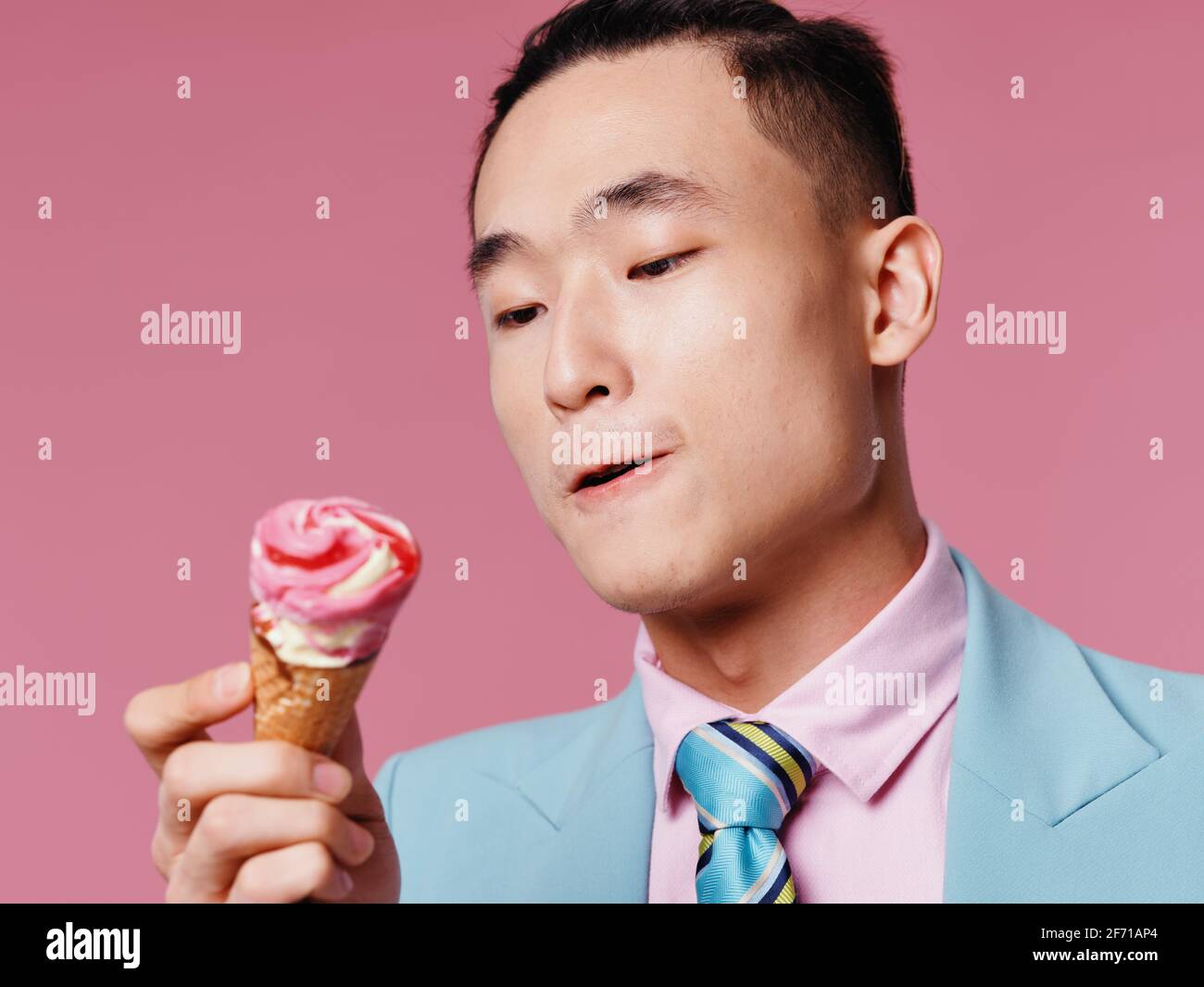 Businessman with ice cream in a cone on a pink background and a blue ...