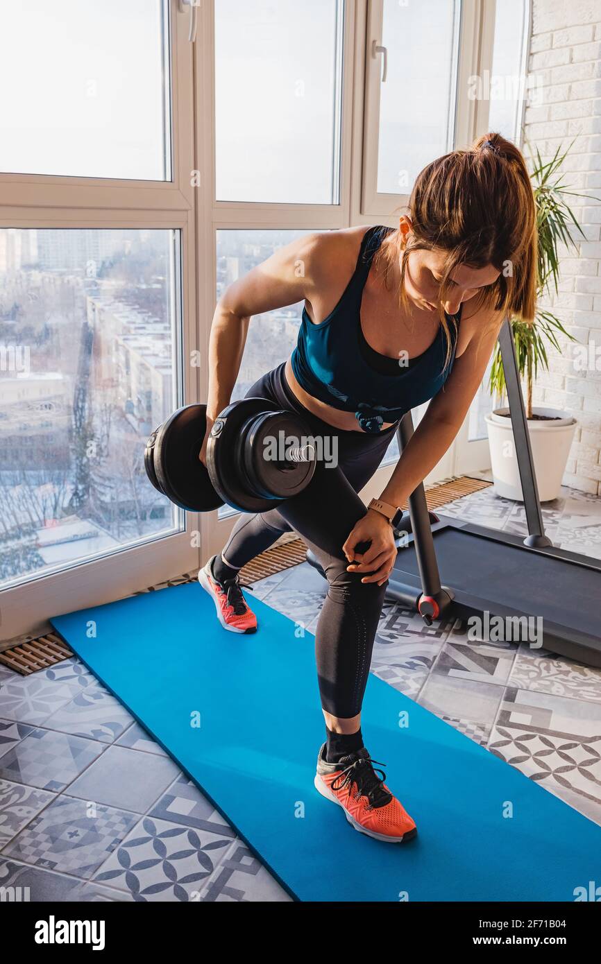 Athletic woman doing dumbbell one arm row exercise Stock Photo - Alamy