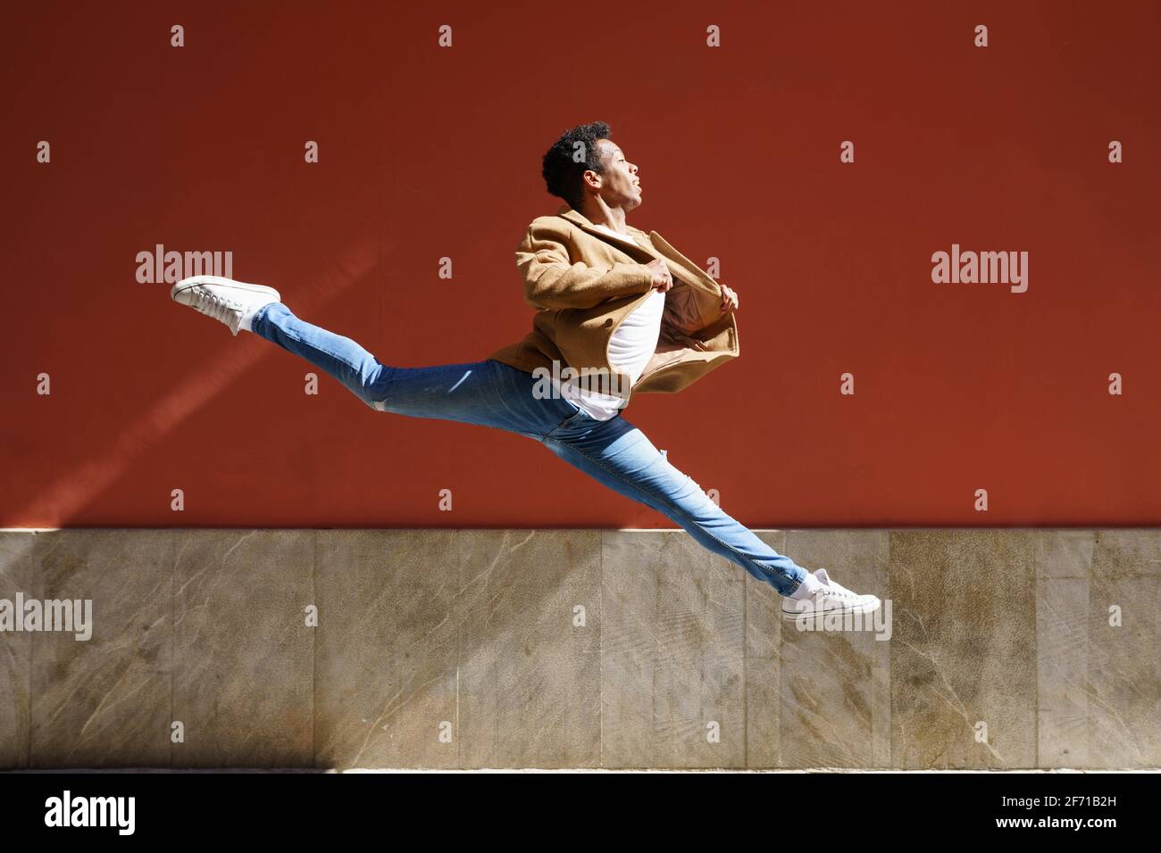 Black athletic man doing an acrobatic jump outdoors Stock Photo - Alamy
