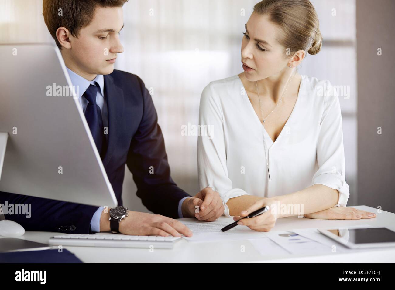 Business people discussing something while sitting in sunny office ...