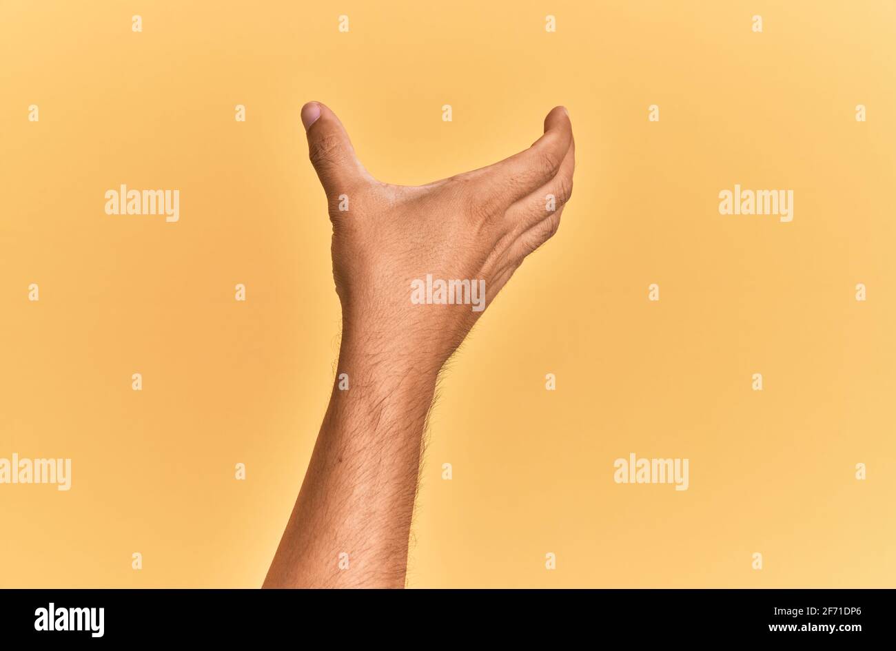 Arm and hand of caucasian man over yellow isolated background holding ...