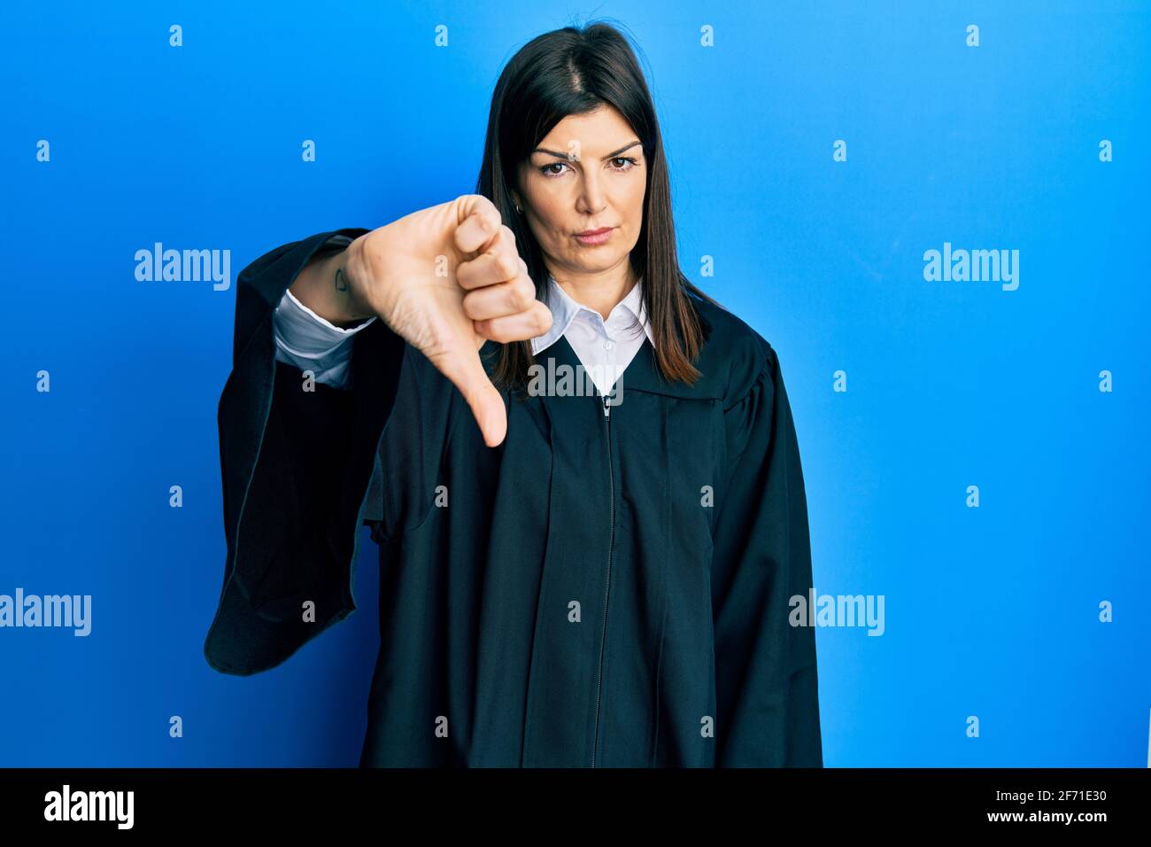 Young hispanic woman wearing judge uniform looking unhappy and angry ...