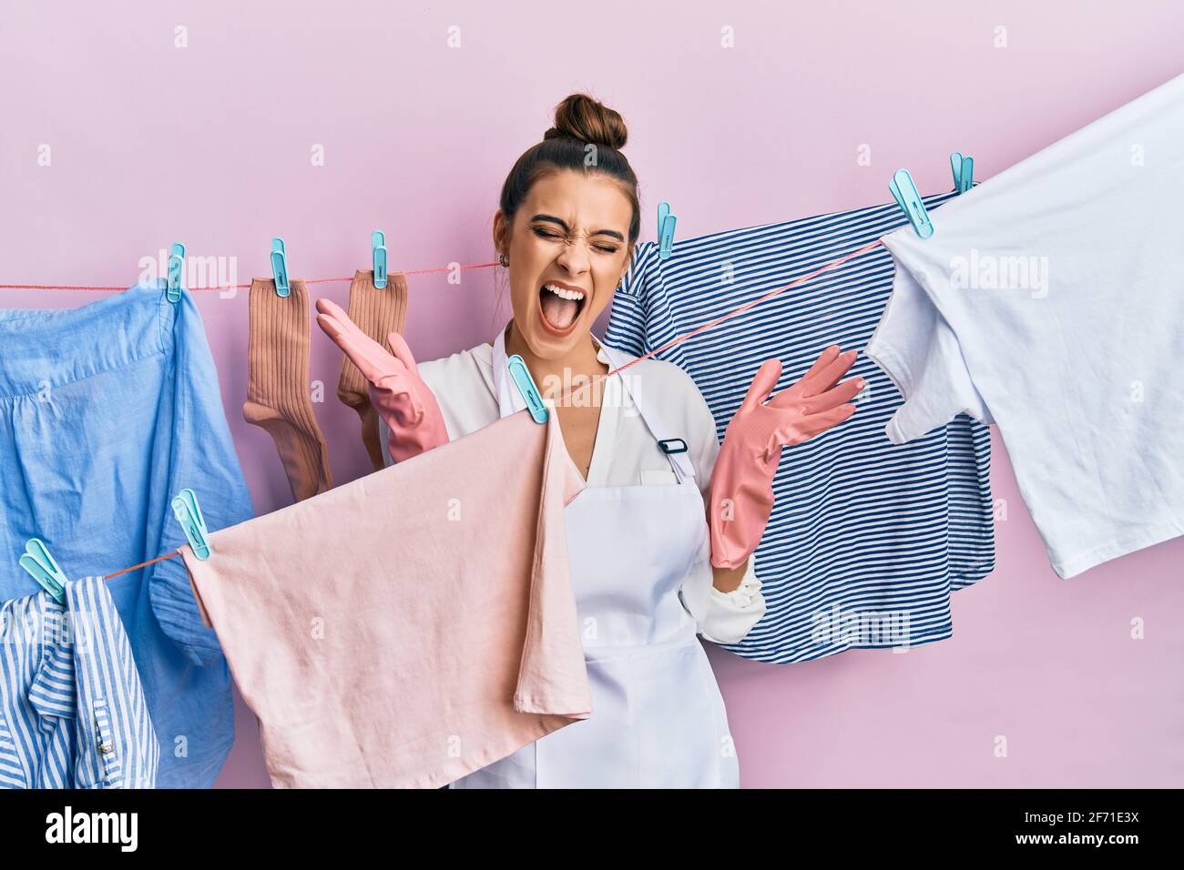 Beautiful brunette young woman washing clothes at clothesline ...