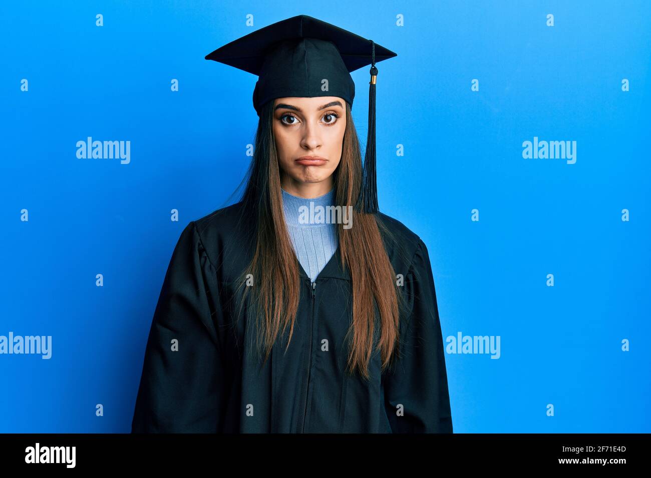 Beautiful brunette young woman wearing graduation cap and ceremony robe ...