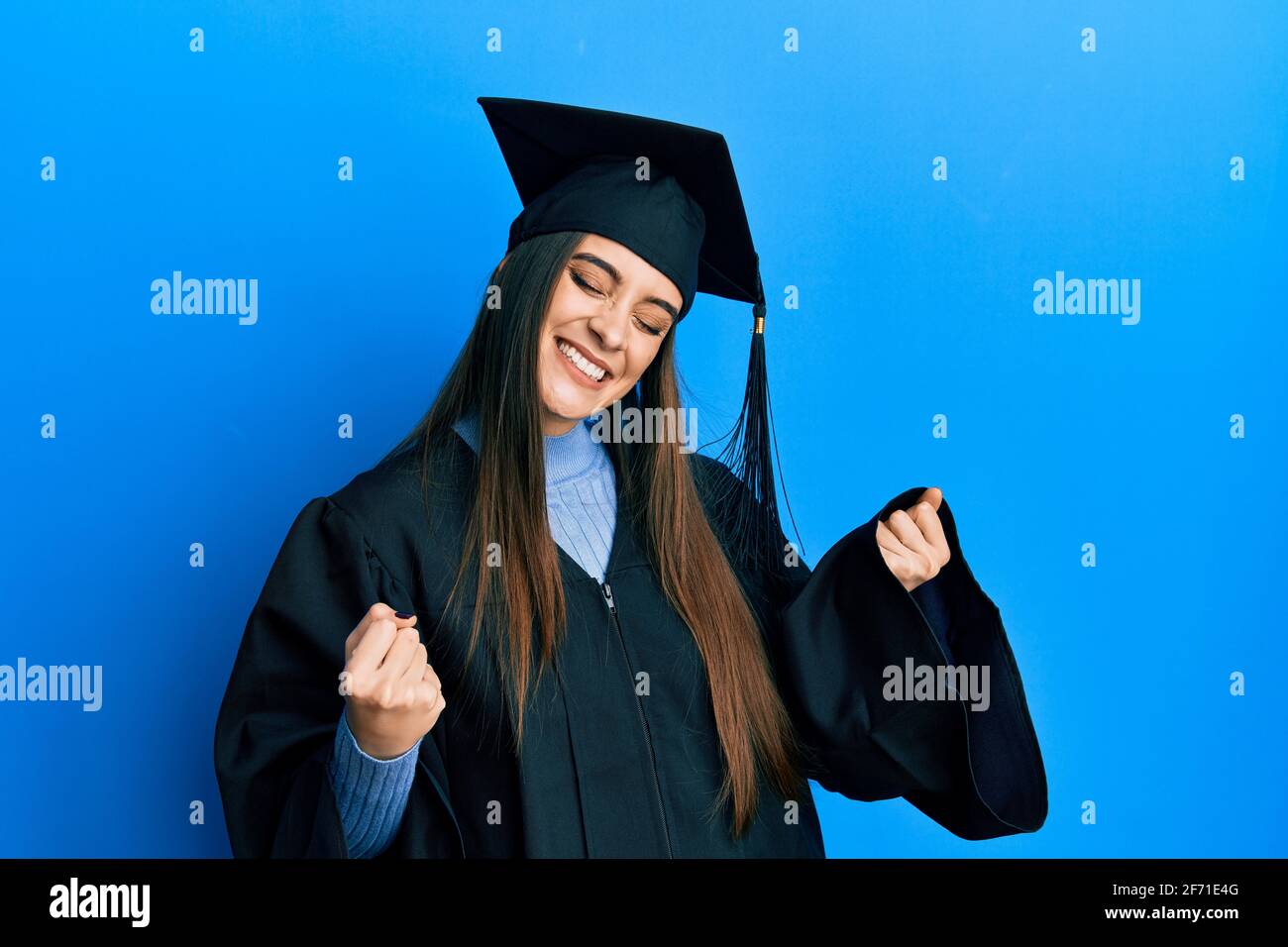 Beautiful brunette young woman wearing graduation cap and ceremony robe ...
