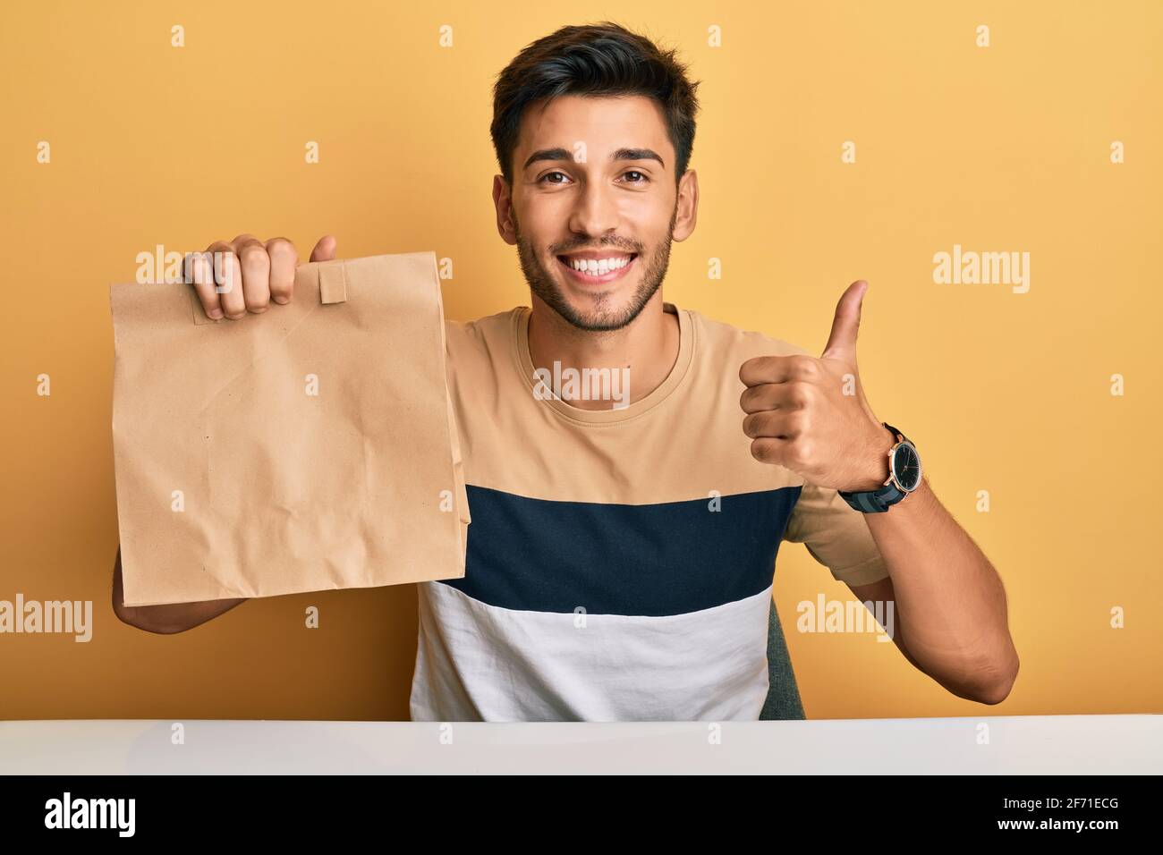 Young handsome man holding take away paper bag smiling happy and ...