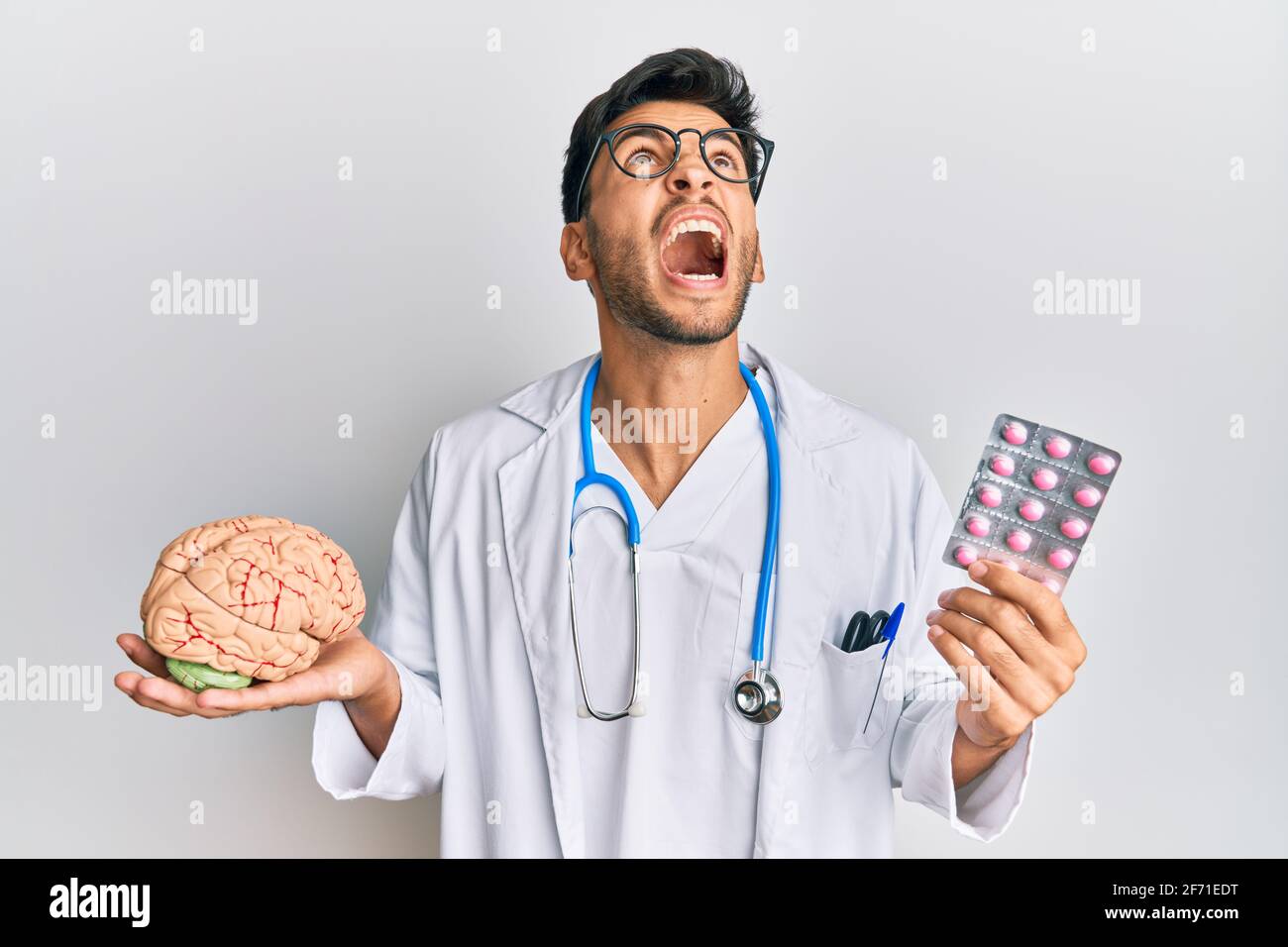 Young handsome man holding brain and pills as mental health concept ...