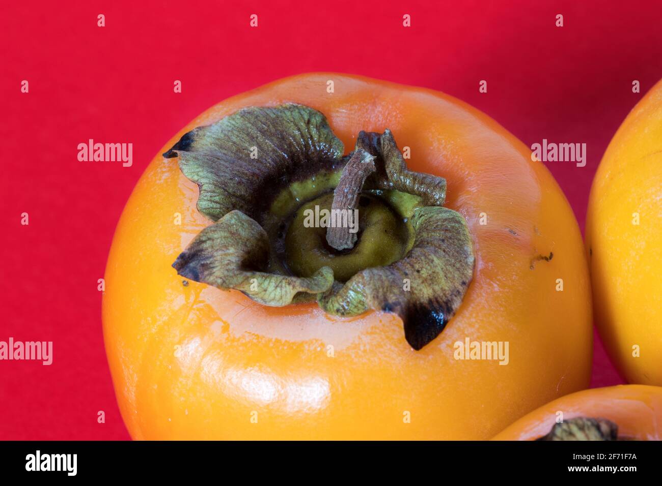 three persimmons on red background Stock Photo - Alamy