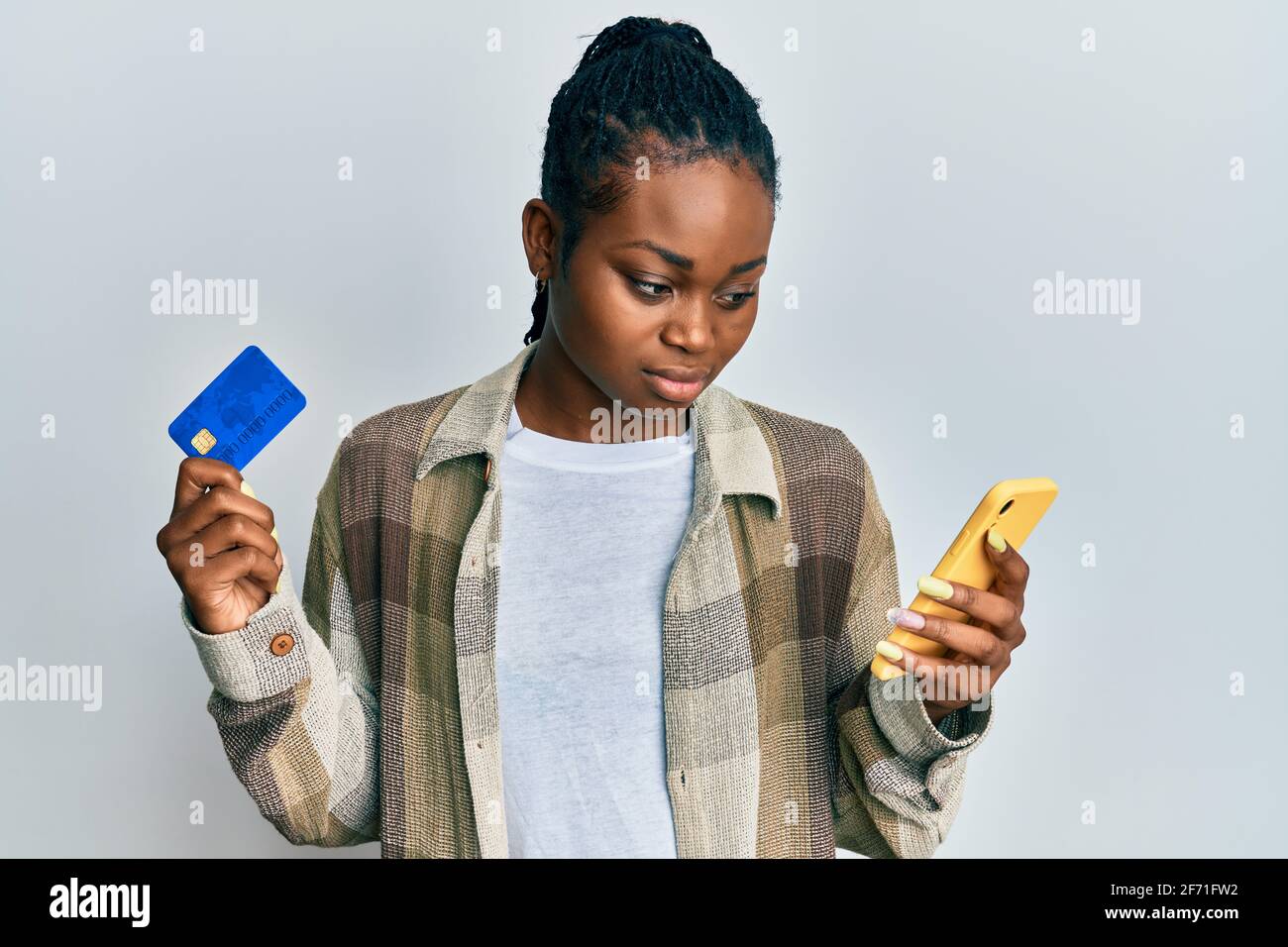 Young african american woman holding smartphone and credit card ...