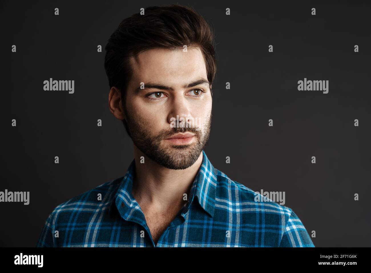 Brunette handsome unshaven guy posing and looking aside isolated over ...