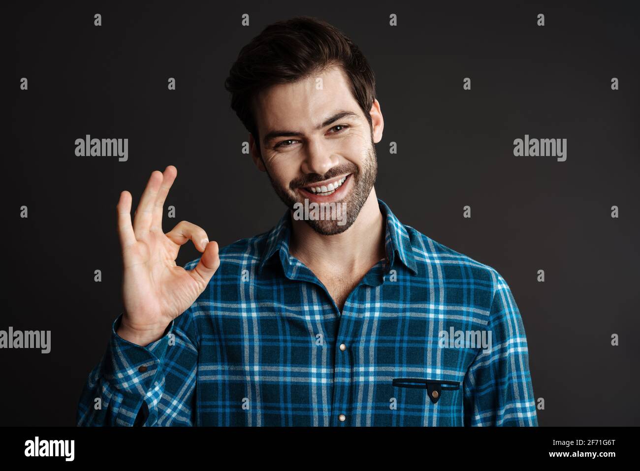 Joyful handsome unshaven guy smiling and showing ok sign isolated over ...