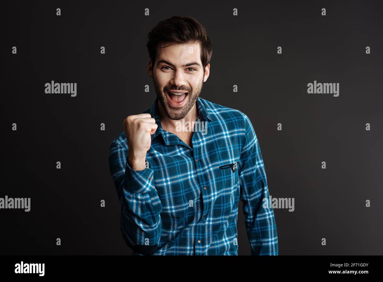 Excited handsome guy screaming and making winner gesture isolated over ...