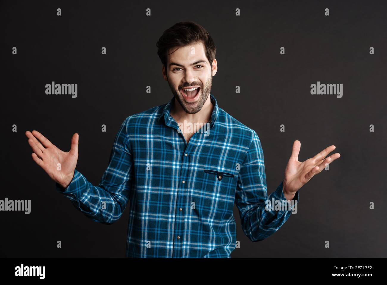 Excited handsome guy posing with throwing up hands isolated over black ...
