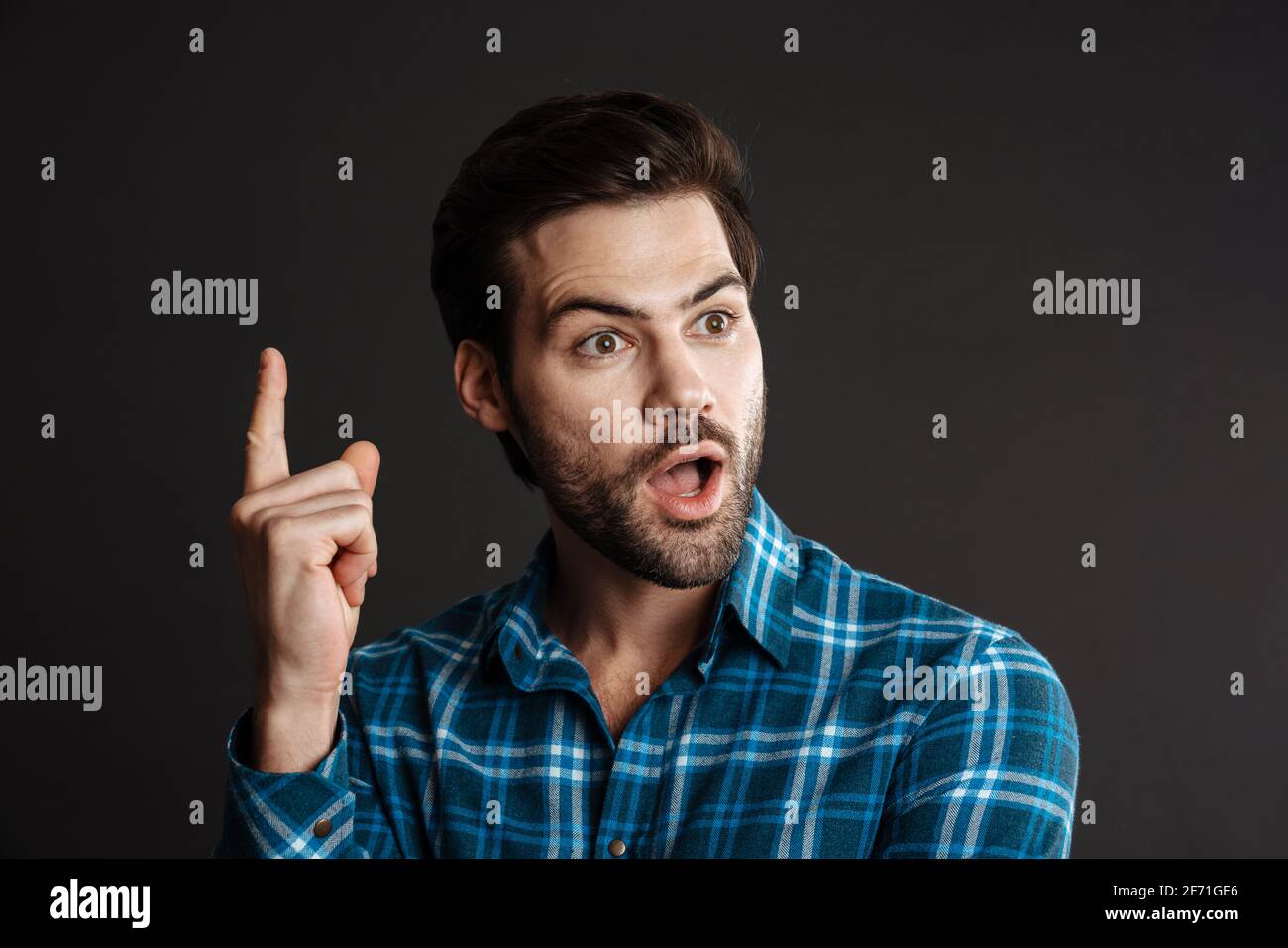 Shocked handsome guy exclaiming and pointing finger upward isolated ...