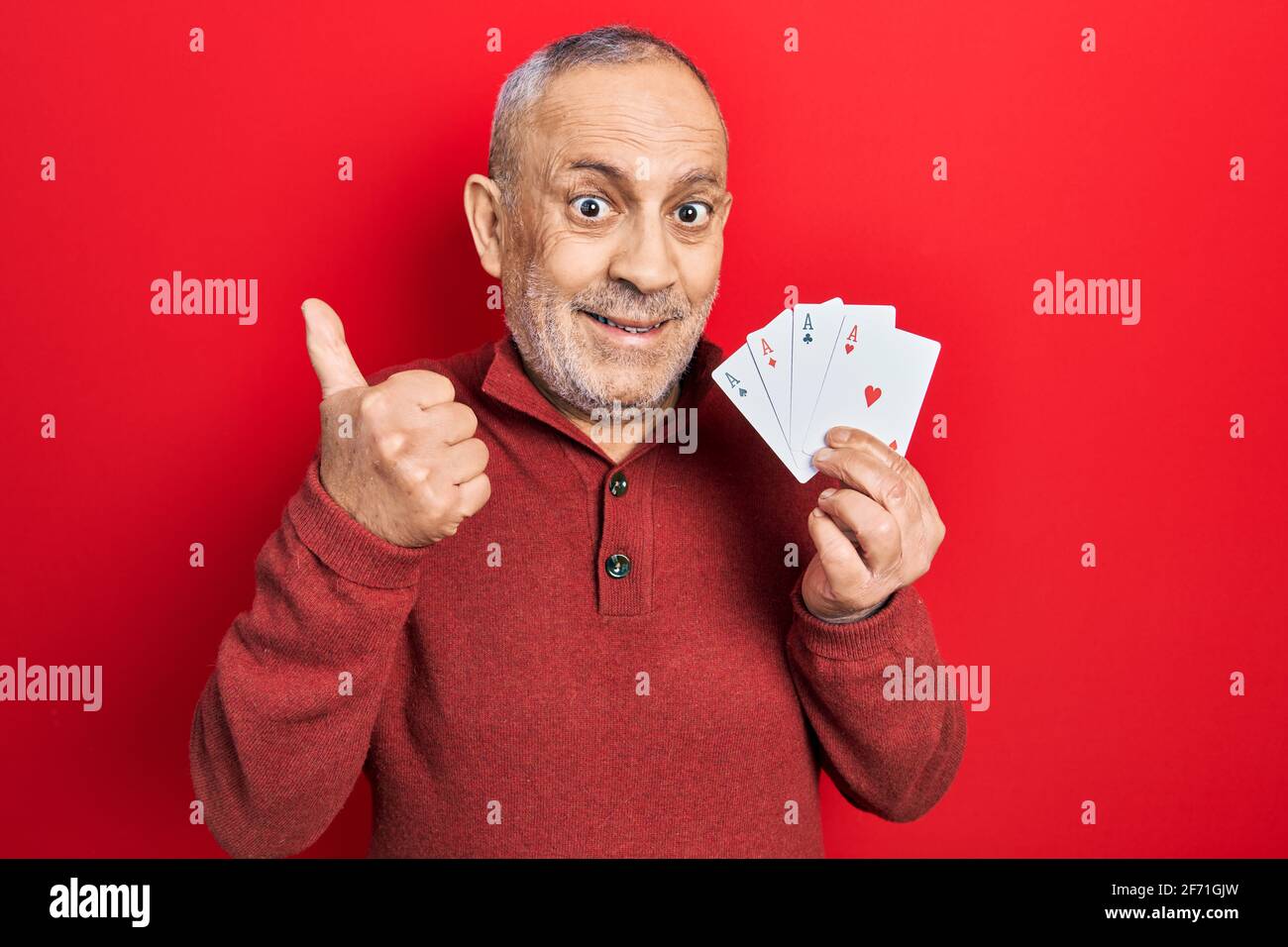 Handsome mature man playing poker holding cards smiling happy and ...