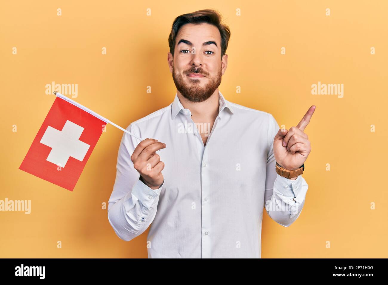 Handsome caucasian man with beard holding switzerland flag smiling ...