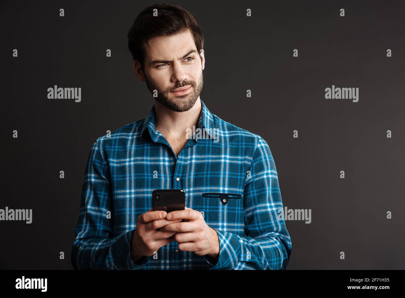 Brooding handsome guy looking aside and using cellphone isolated over ...