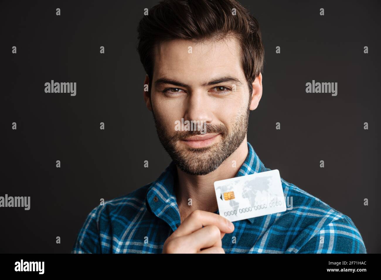 Happy unshaven guy smiling while posing with credit card isolated over ...