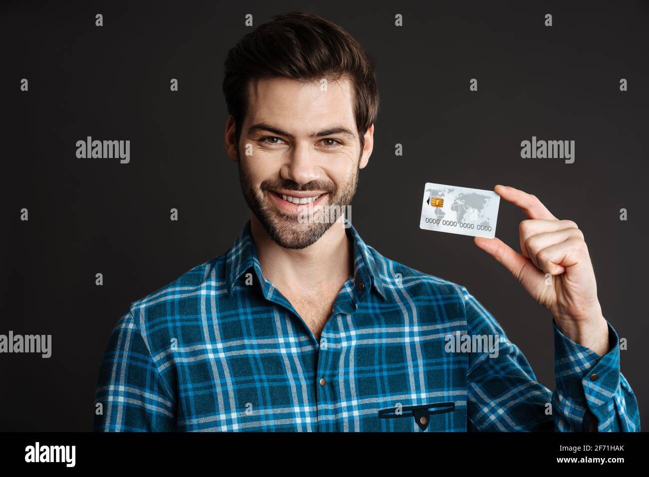 Happy unshaven guy smiling while posing with credit card isolated over ...