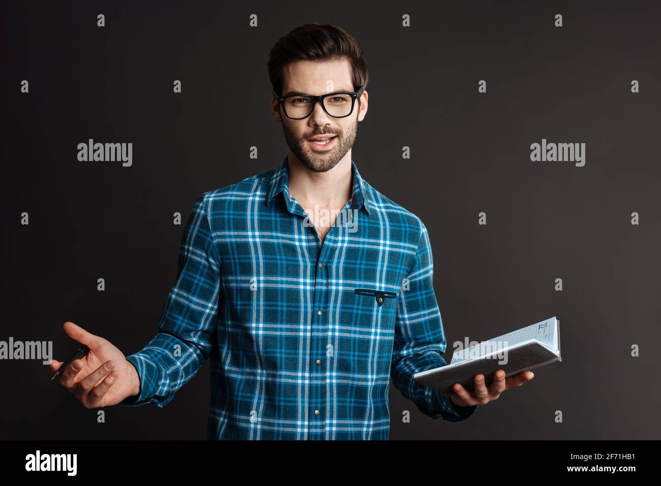 Smiling handsome guy in eyeglasses posing with calendar isolated over ...