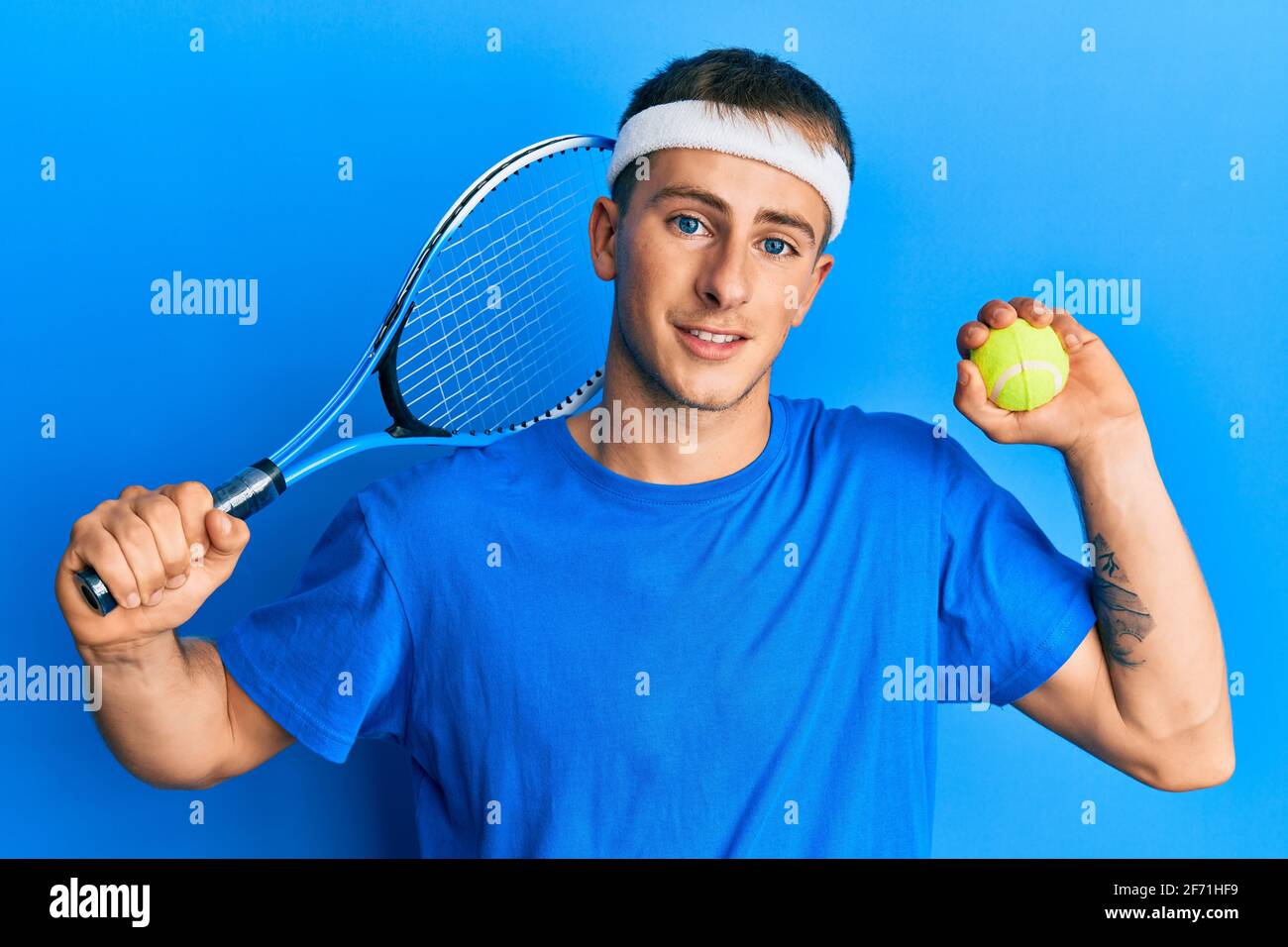 Young caucasian man playing tennis holding racket and ball smiling with ...