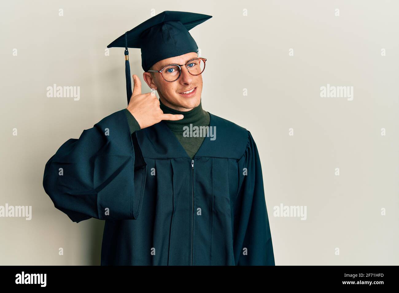 Young caucasian man wearing graduation cap and ceremony robe smiling ...