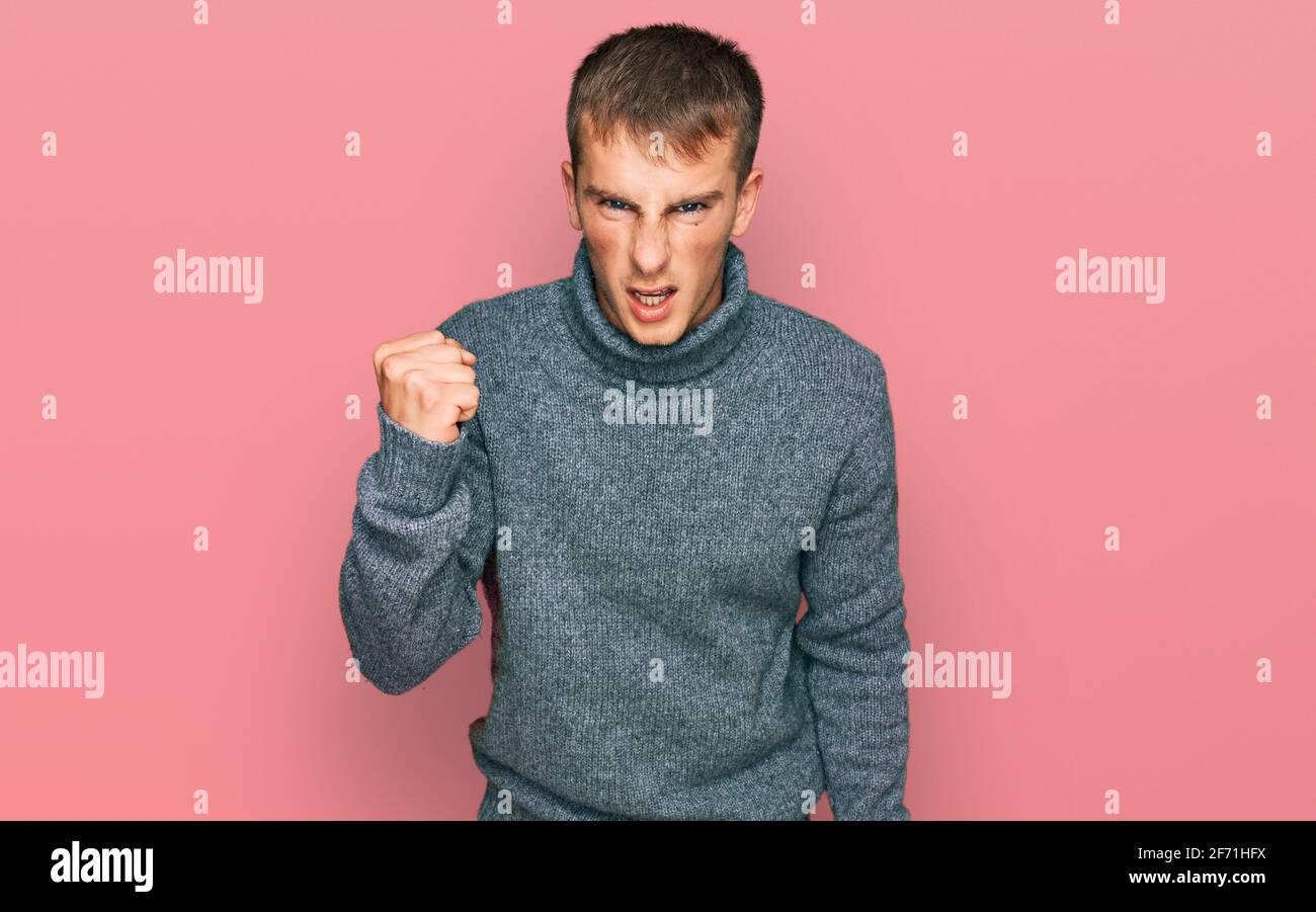 Young blond man wearing casual clothes angry and mad raising fist ...