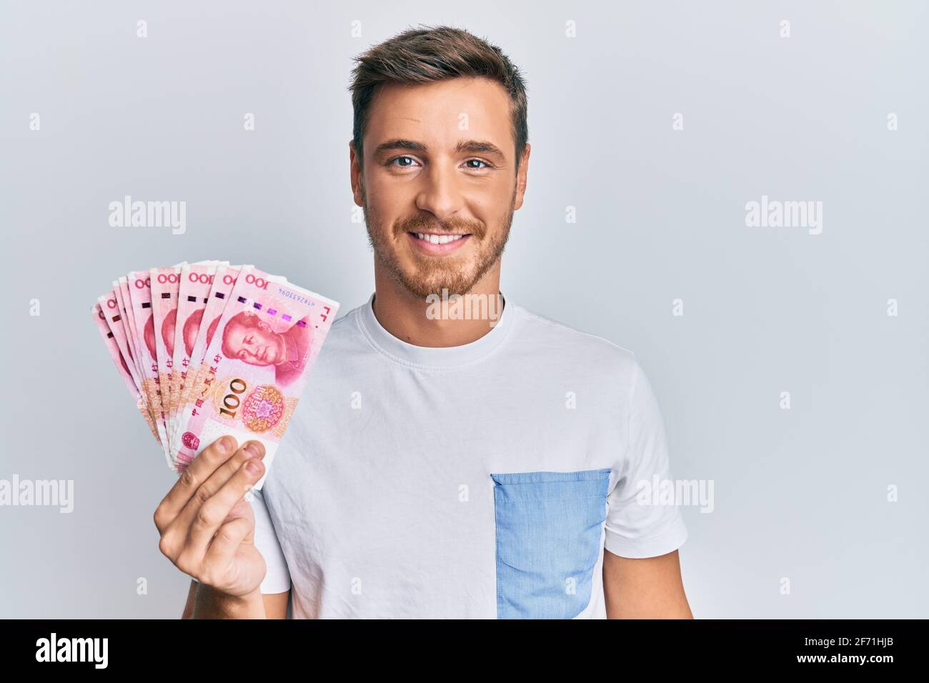 Handsome caucasian man holding 100 yuan chinese banknotes looking ...