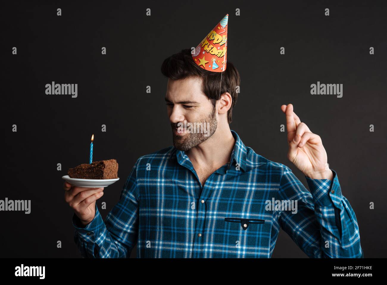 Happy guy holding fingers crossed while posing with birthday cake ...