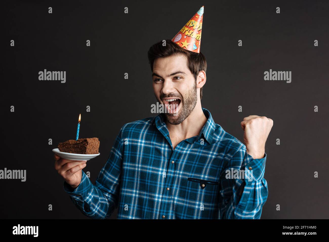 Excited guy making winner gesture while posing with birthday cake ...