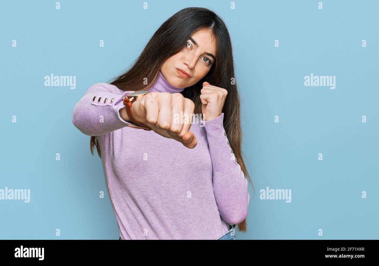 Young beautiful teen girl wearing turtleneck sweater punching fist to ...