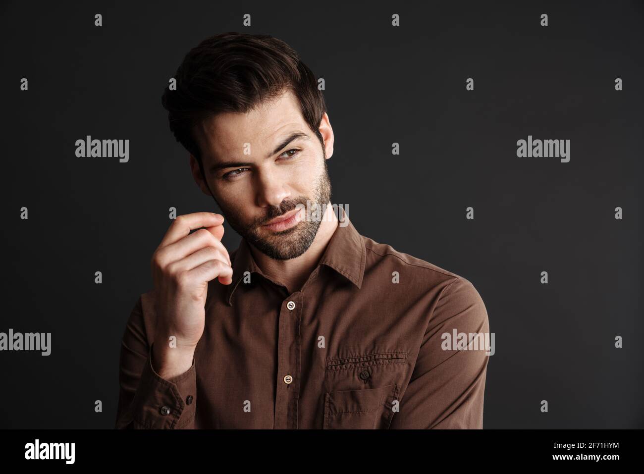Brunette handsome unshaven guy posing and looking aside isolated over ...