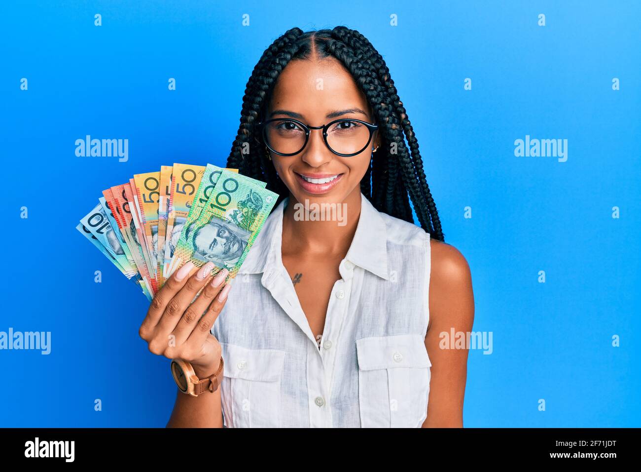 Beautiful hispanic woman holding australian dollars looking positive ...
