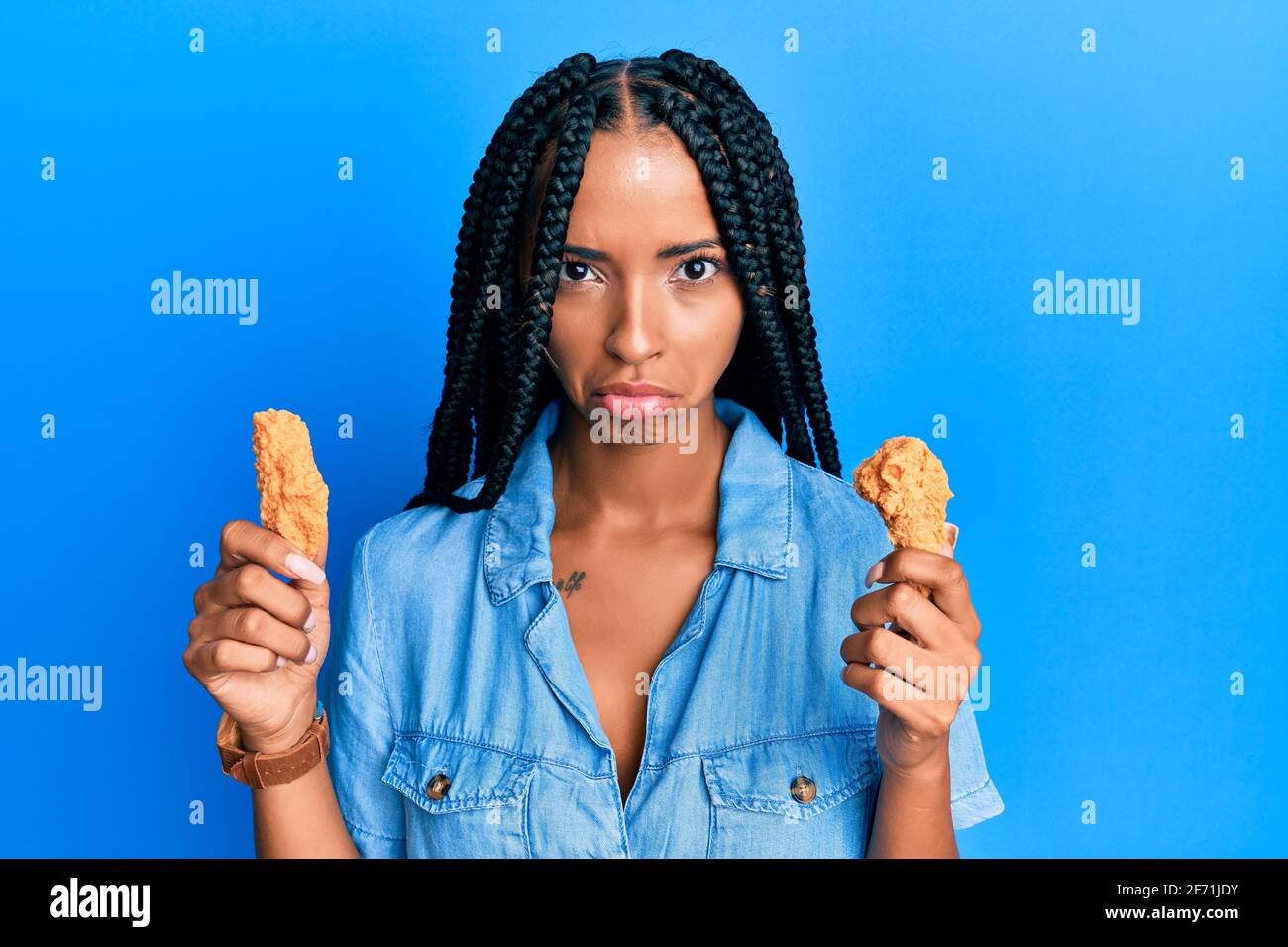 Beautiful hispanic woman eating chicken wings depressed and worry for ...