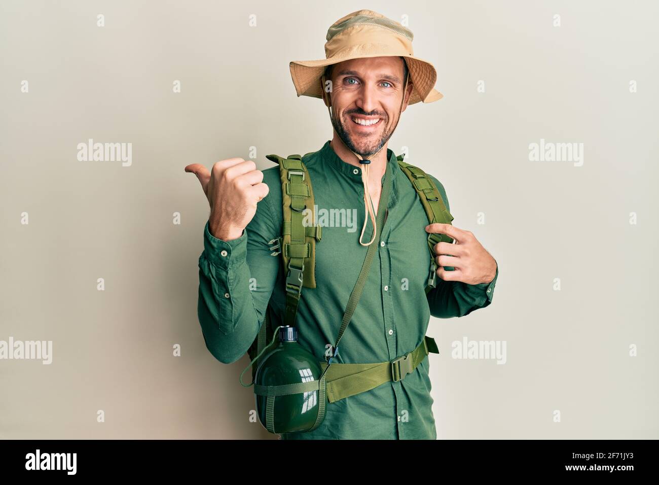 Handsome man with beard wearing explorer hat and backpack pointing to ...