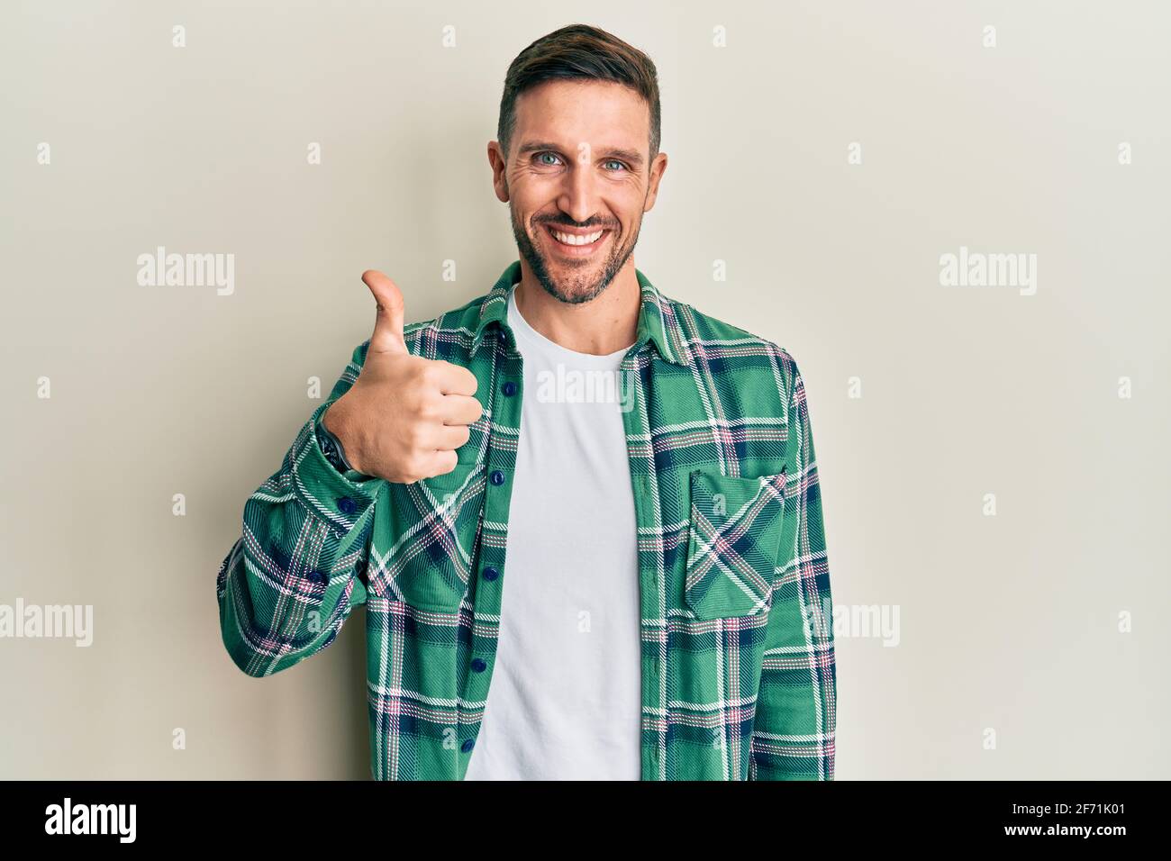 Handsome man with beard wearing casual clothes doing happy thumbs up ...