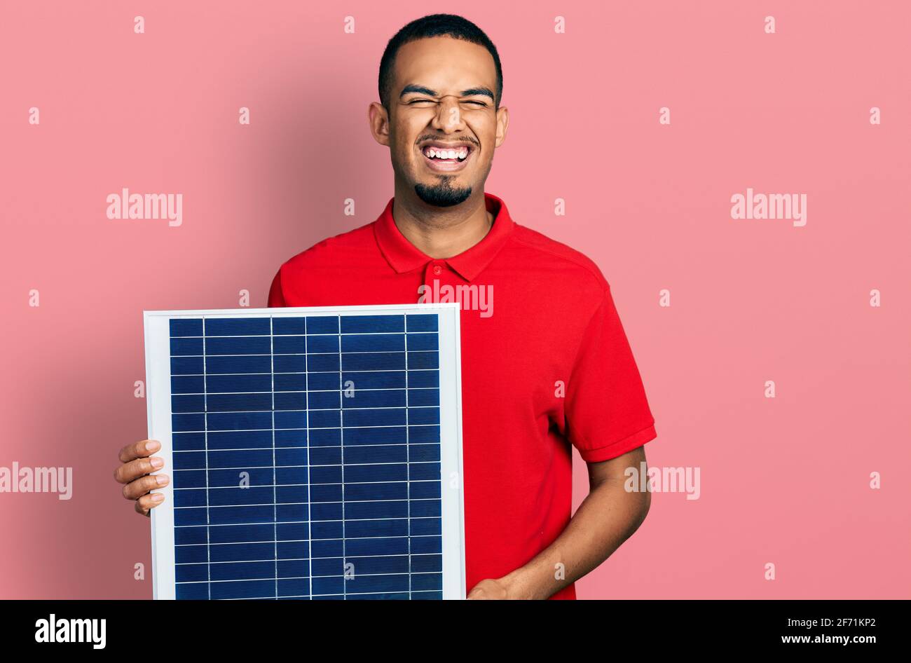 Young african american man holding photovoltaic solar panel smiling and ...