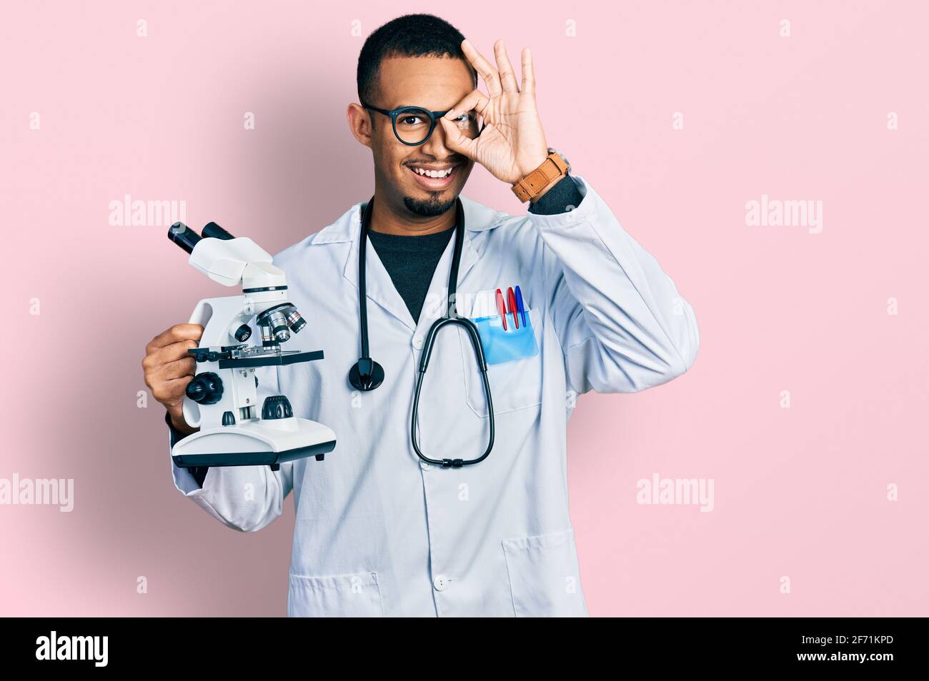 Young african american man wearing scientist uniform holding microscope ...