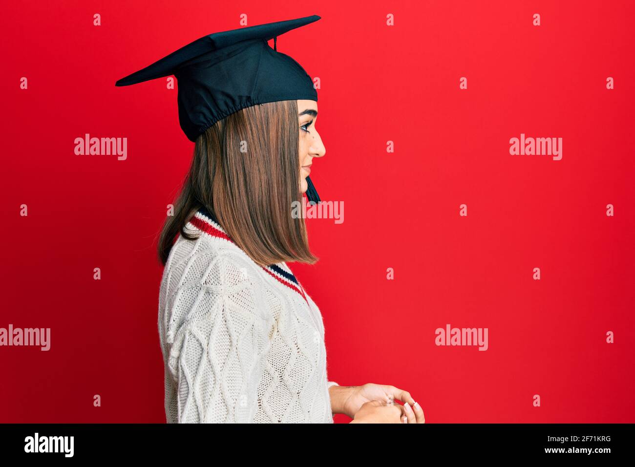 Young brunette girl wearing graduation cap looking to side, relax ...