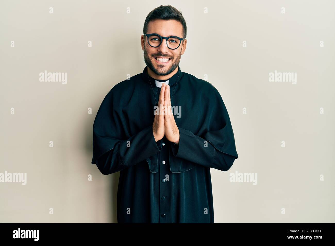 Young hispanic man wearing priest uniform standing over white ...