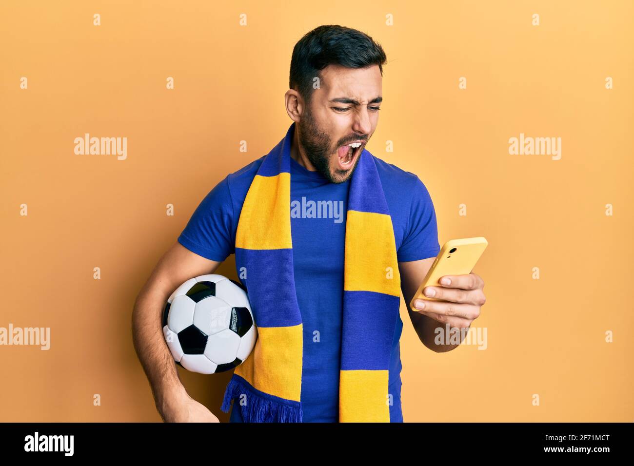 Young hispanic man football hooligan holding soccer ball using ...
