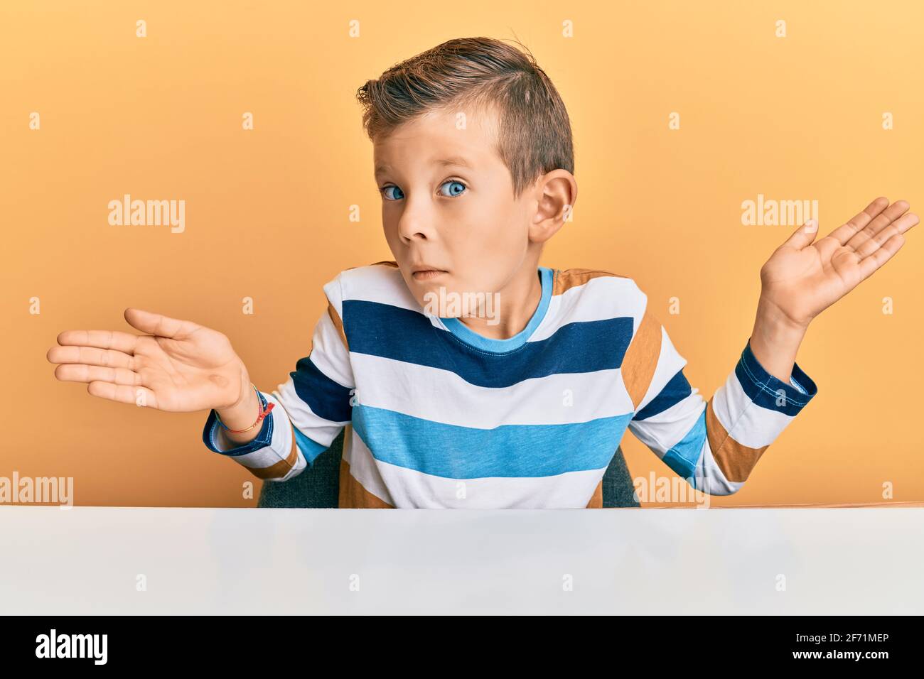 Adorable caucasian kid wearing casual clothes sitting on the table ...