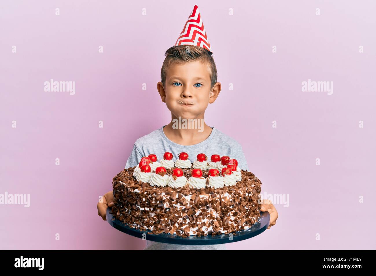 Adorable caucasian kid celebrating birthday with cake puffing cheeks ...