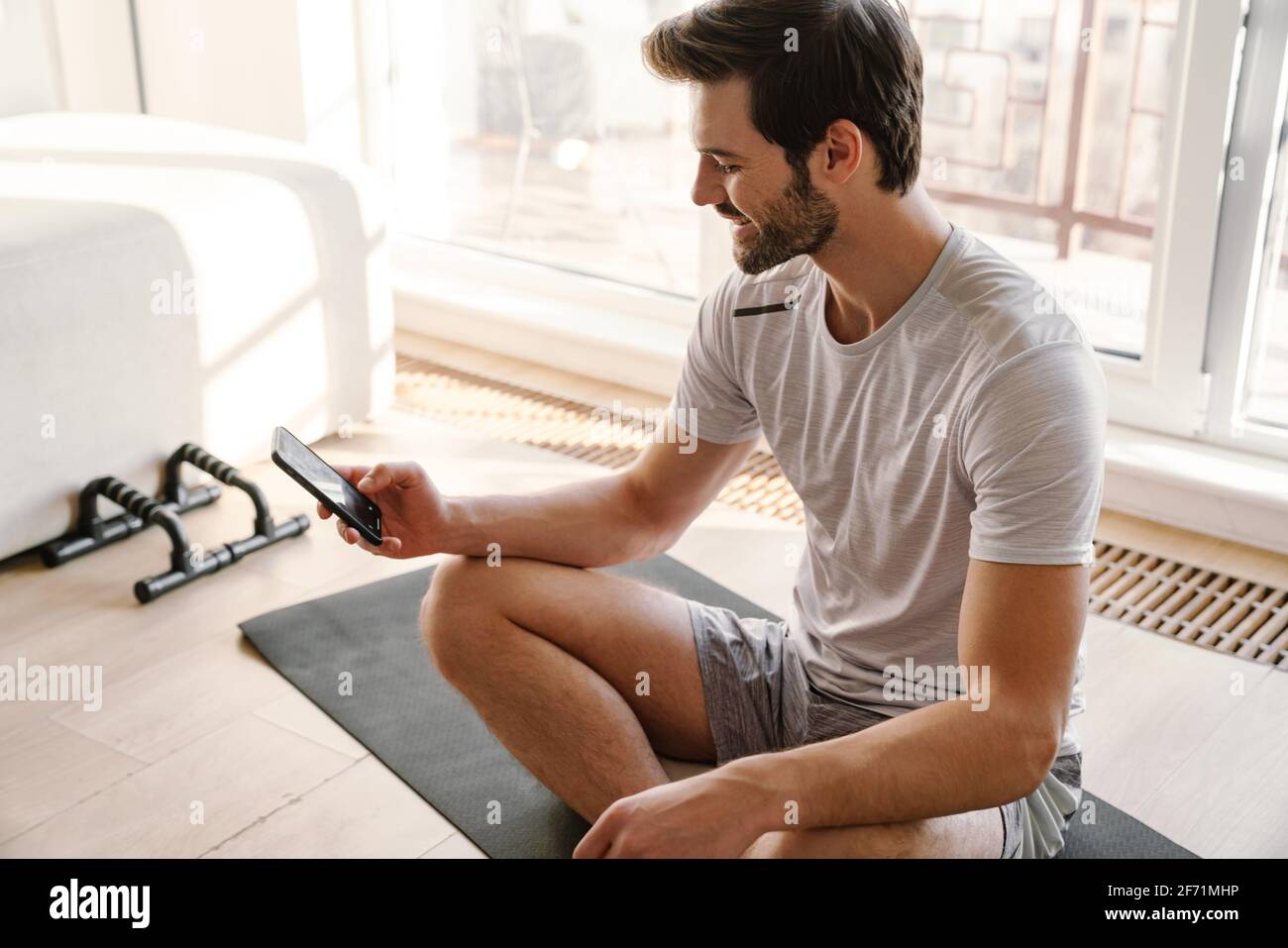 Happy athletic handsome man using mobile phone while working out at ...