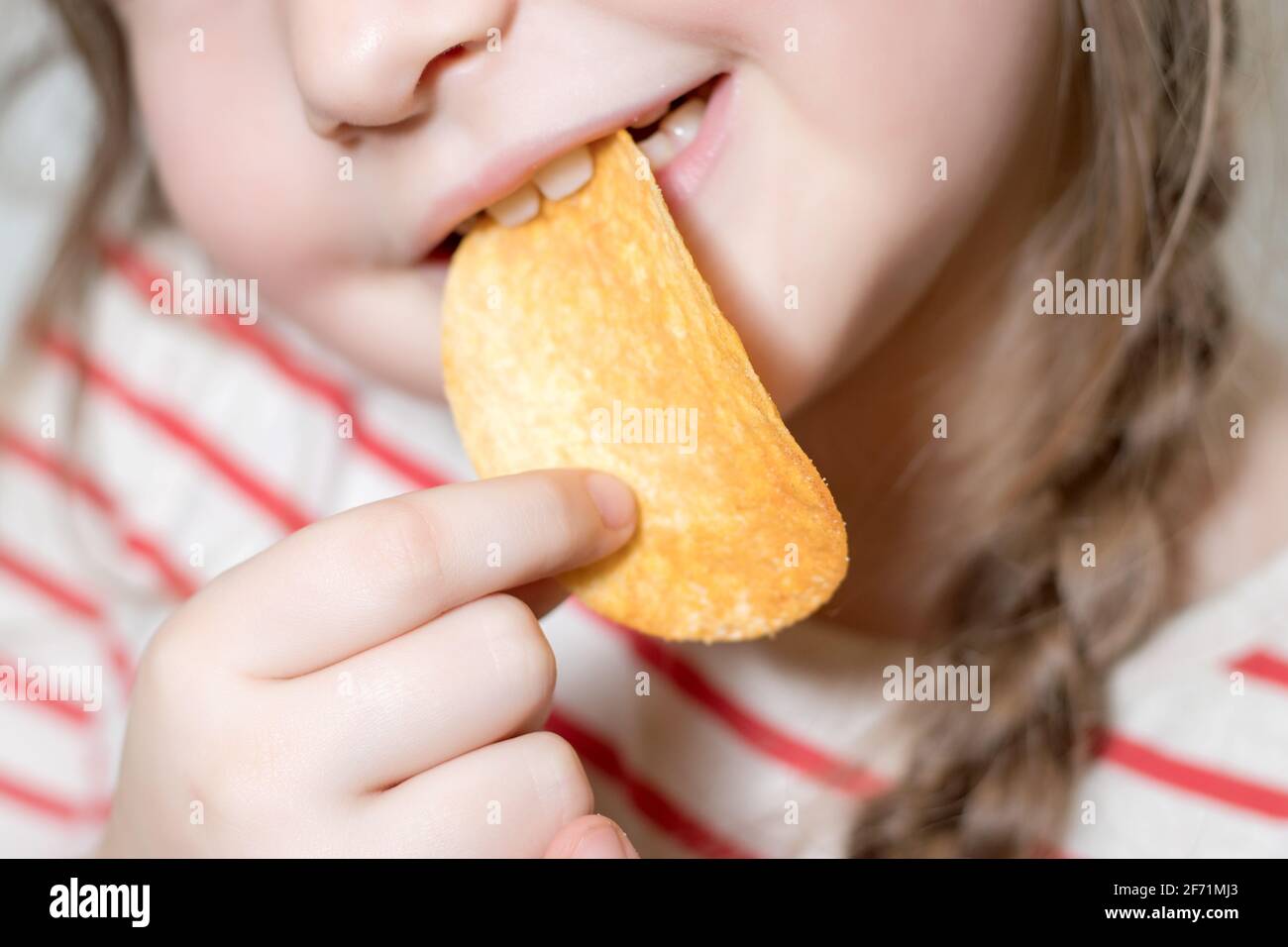 little girl eating a potato chips Stock Photo - Alamy