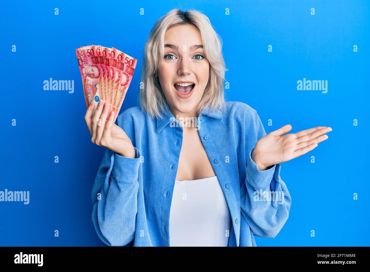 Young blonde girl holding philippine peso banknotes celebrating ...