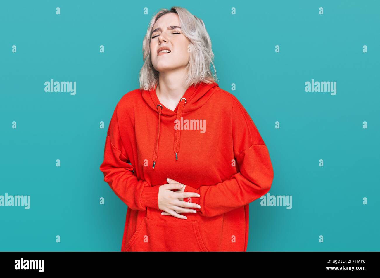 Young blonde girl wearing casual clothes with hand on stomach because ...